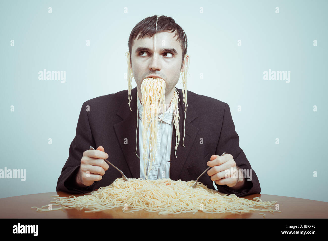 Overeating and consumerism concept. Silly nasty businessman eating ...