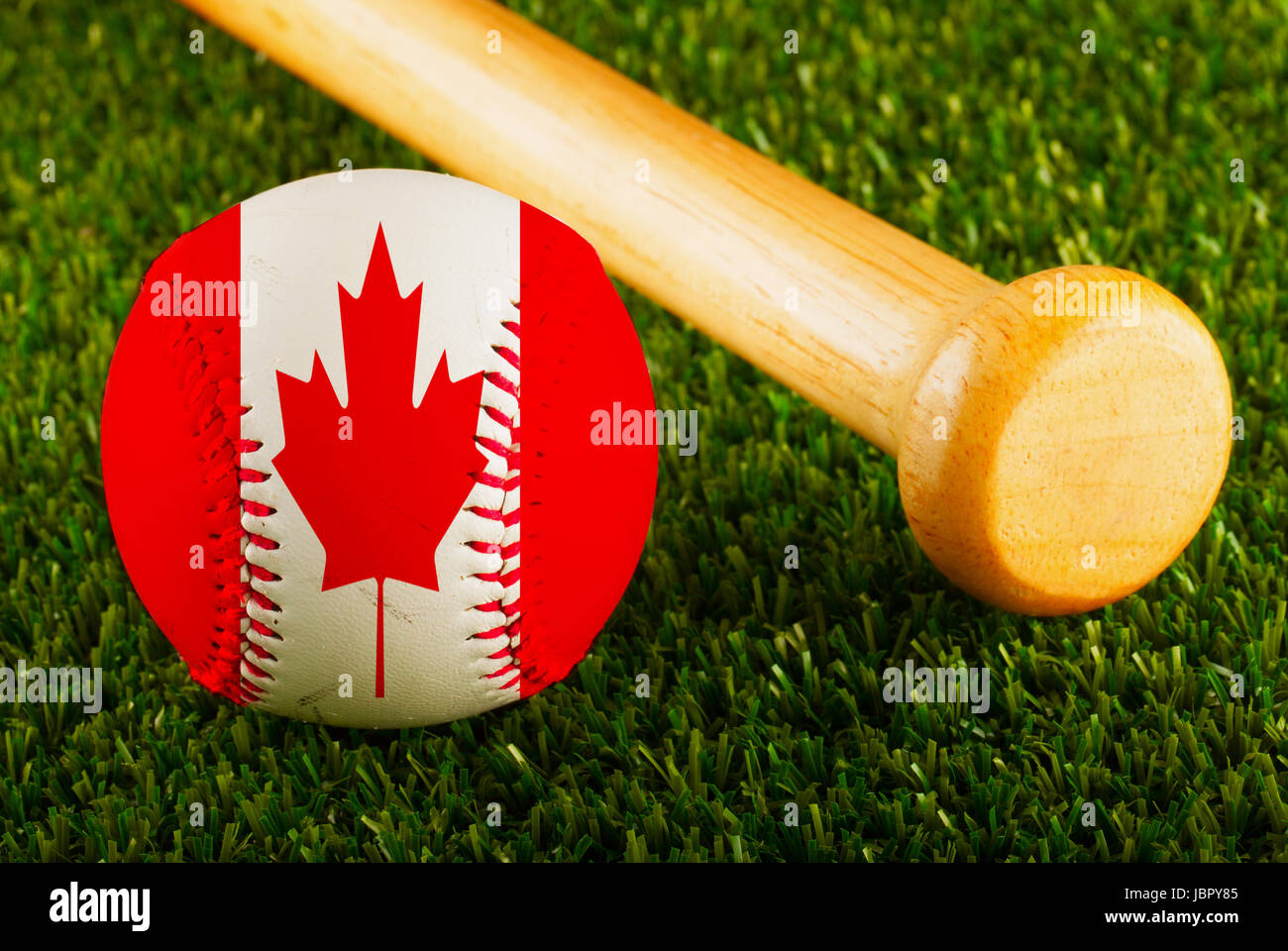 Baseball with Canada flag and bat over a background of green grass ...