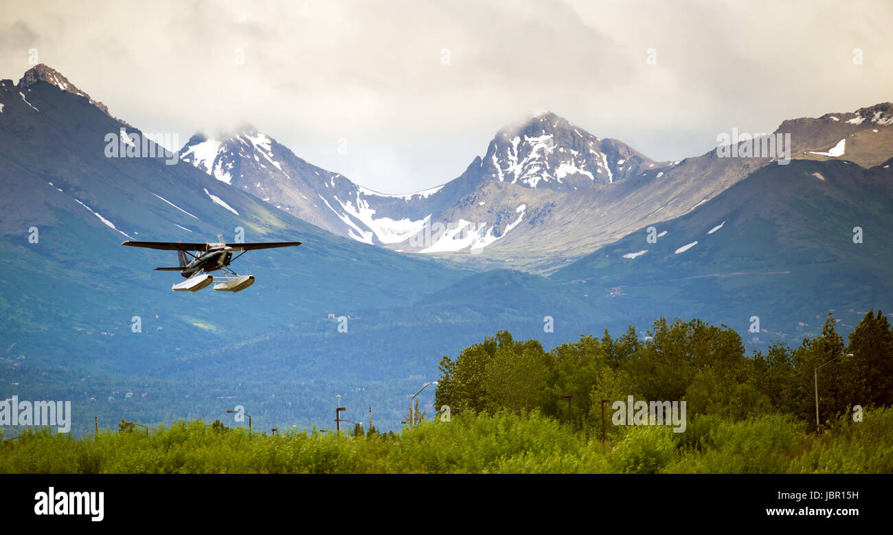 A bush plane performs landing in Alaska with Chugach Mountains in the ...