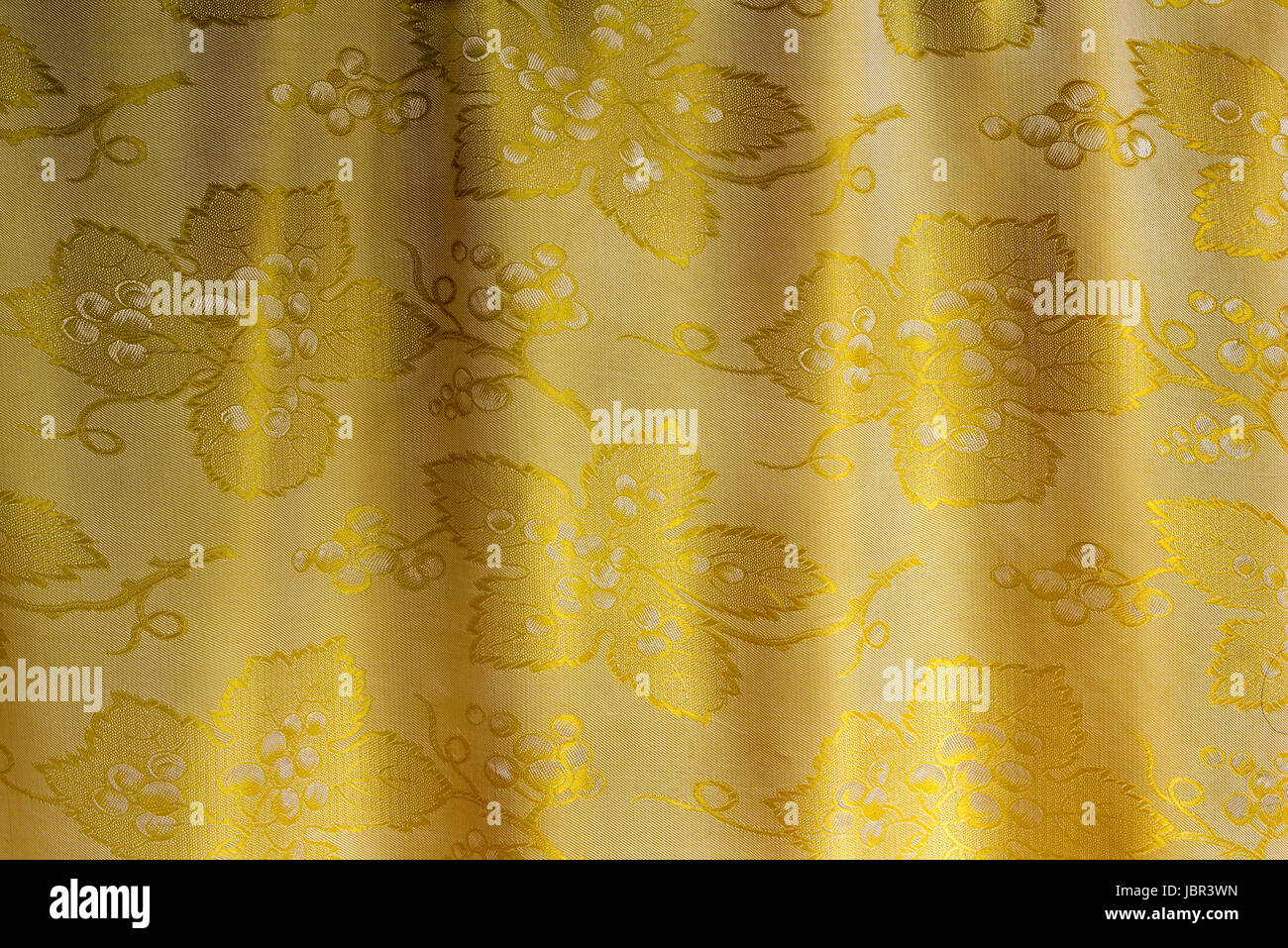 Beautifully draped silk fabric of golden color with an ornament. . It ...