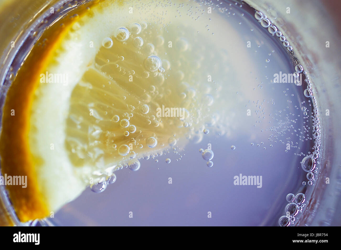 Nahaufname einer Zitronenscheibe in einem perlenden Getränk von oben ...