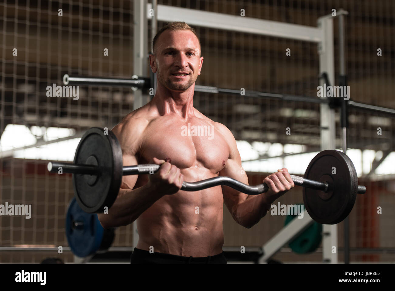 Athlete In The Gym Performing Biceps Curls With A Barbell Stock Photo ...