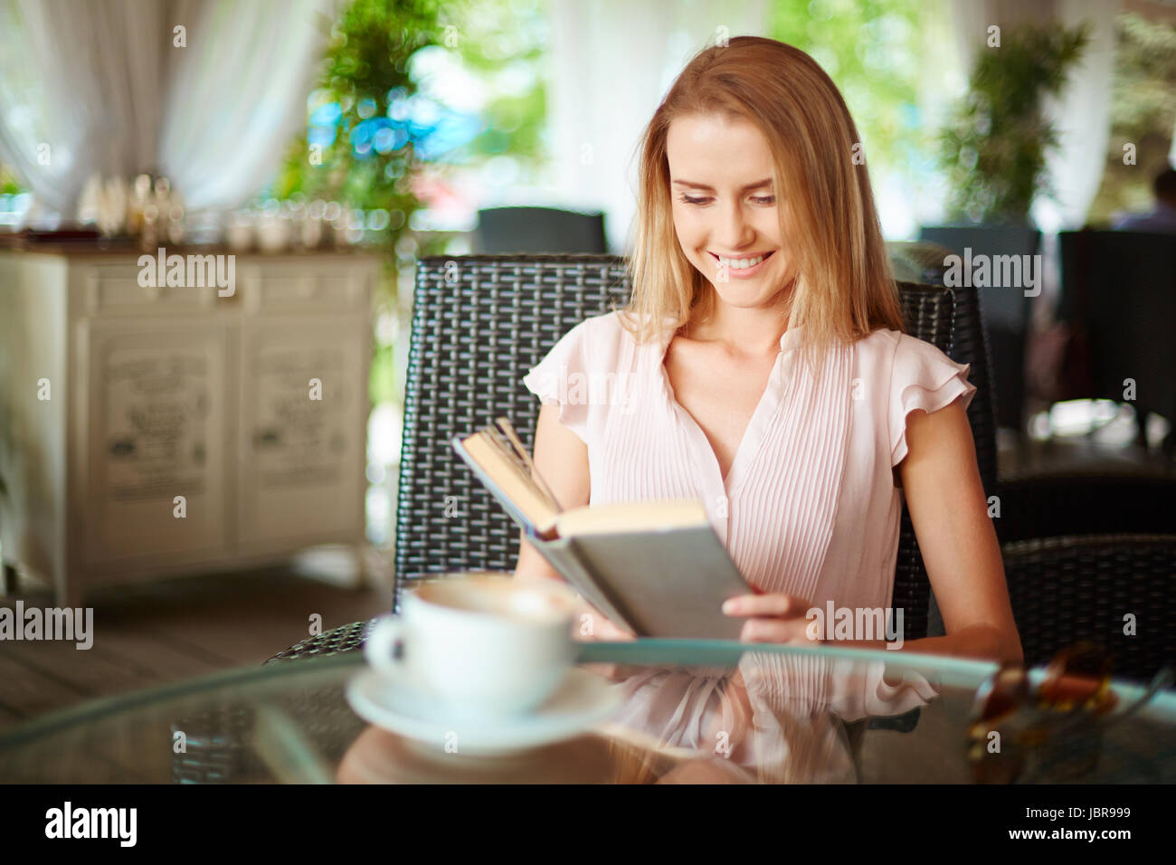 Portrait of cute girl reading a book in cafe Stock Photo - Alamy