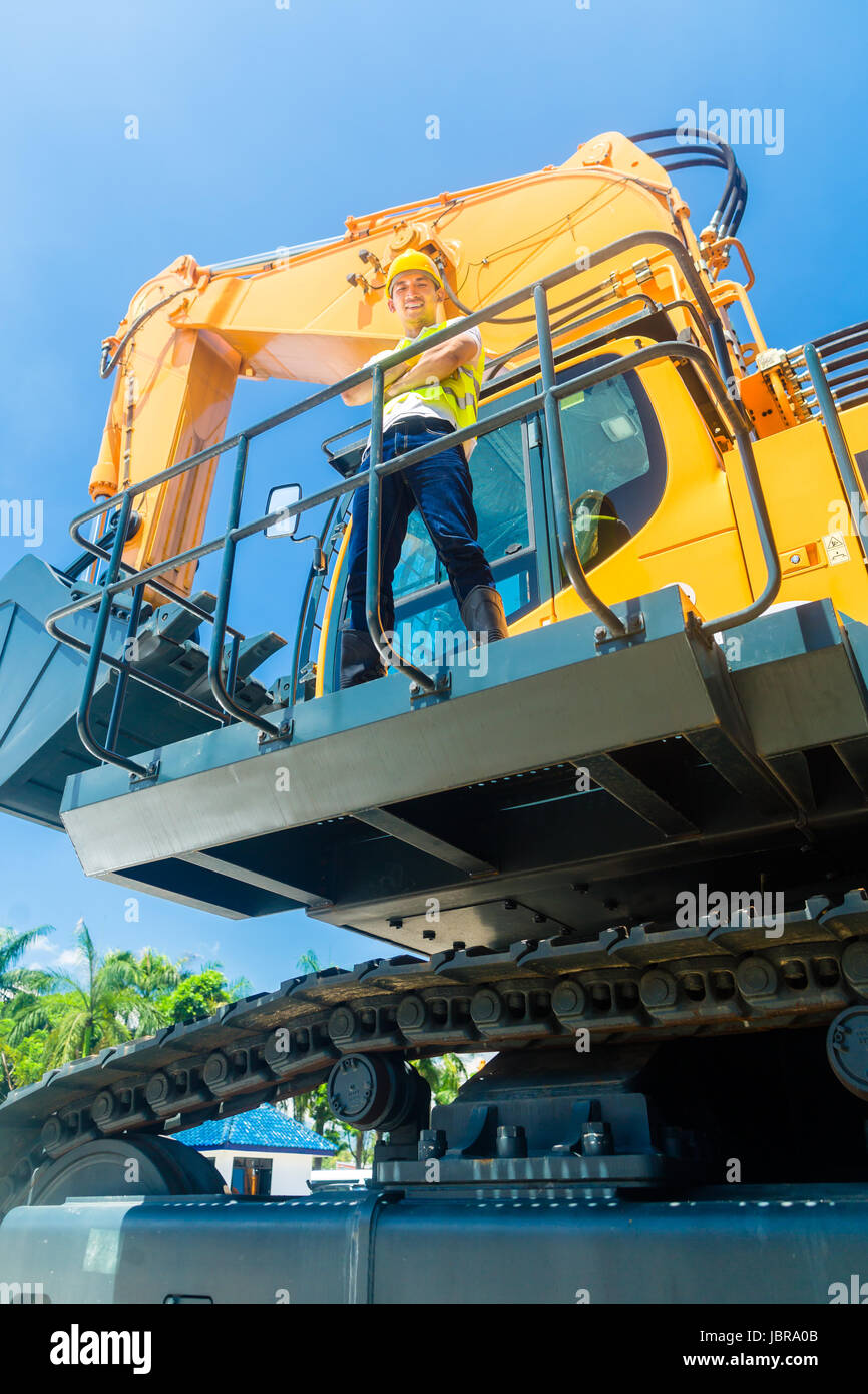 Asian driver standing on construction machinery on building site Stock ...
