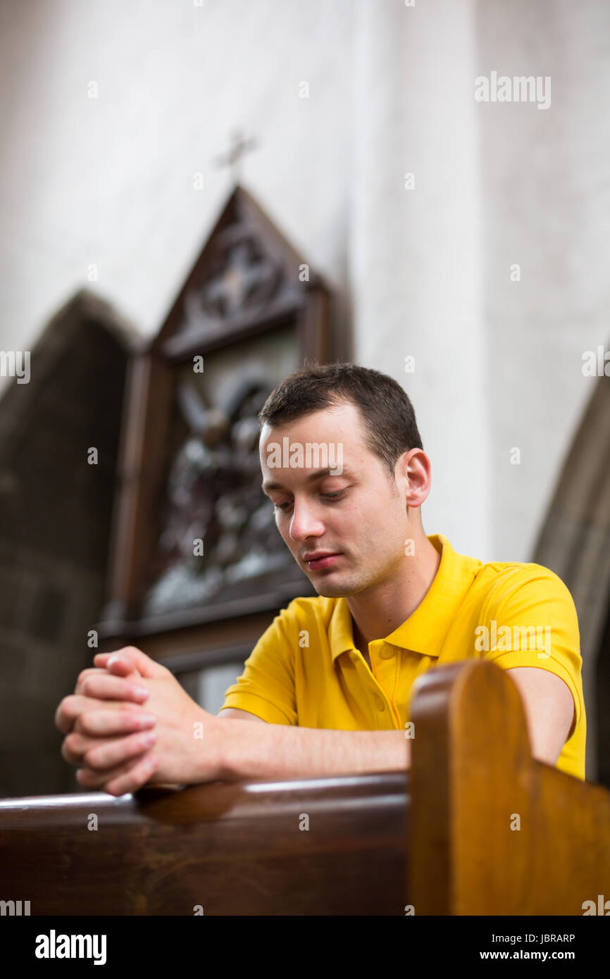 Handsome young man praying in a church Stock Photo - Alamy