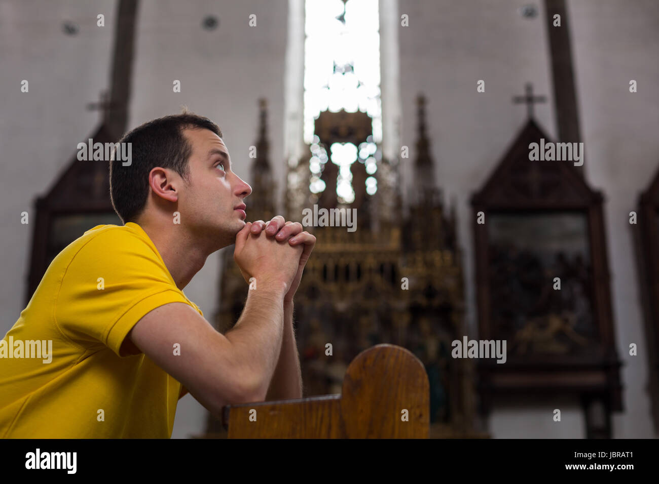 Handsome young man praying in a church Stock Photo - Alamy