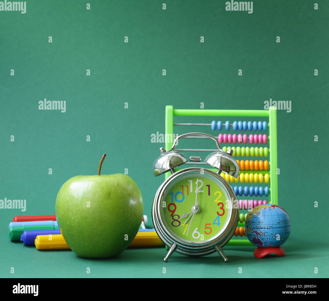 School supplies and apple on a green background Stock Photo - Alamy