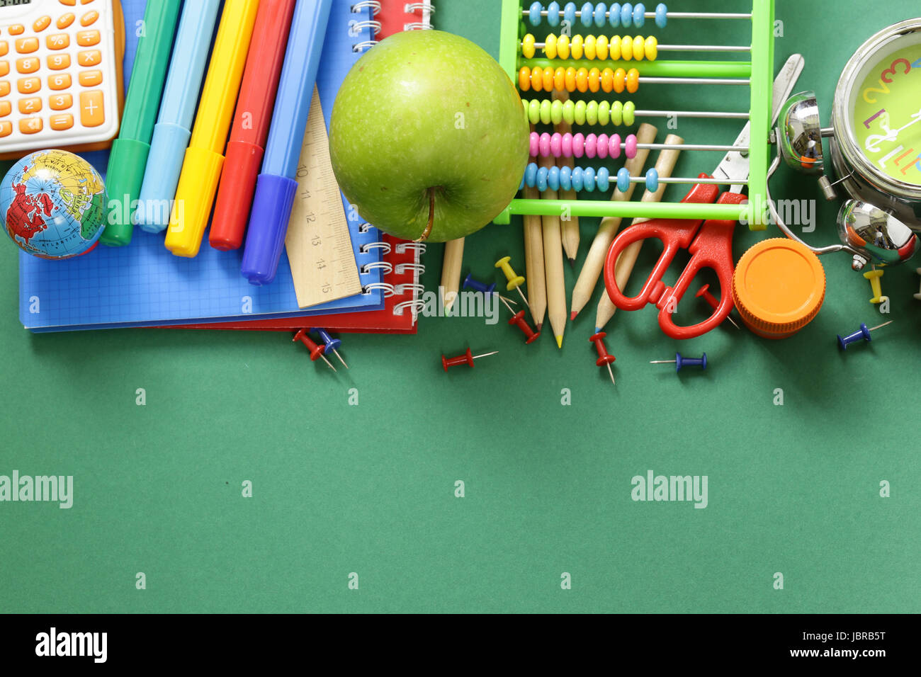 School supplies and apple on a green background Stock Photo - Alamy