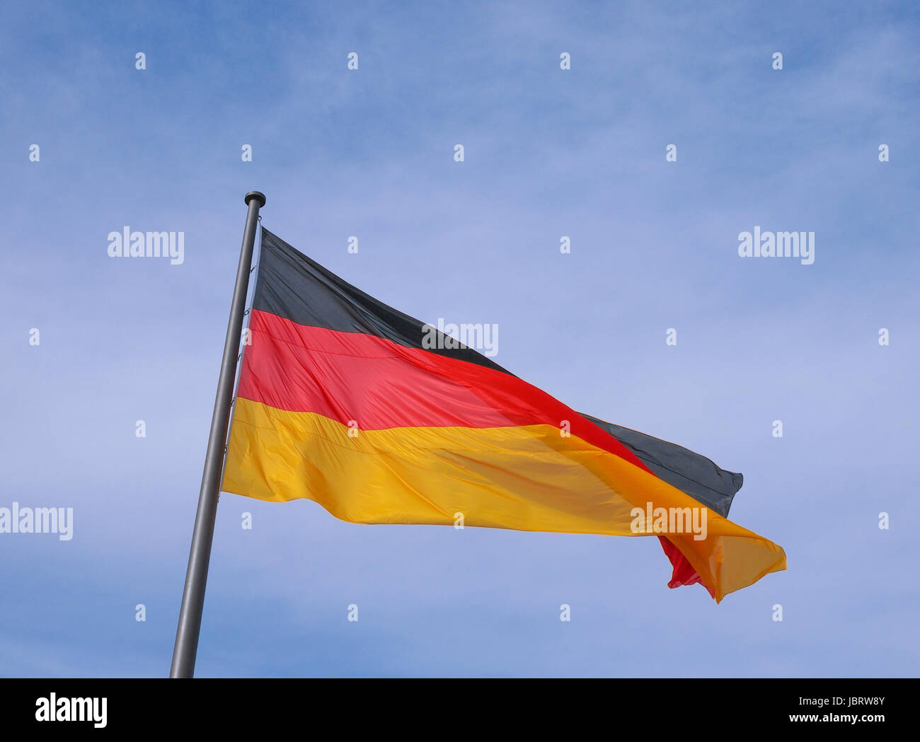 The national German flag of Germany over blue sky Stock Photo - Alamy