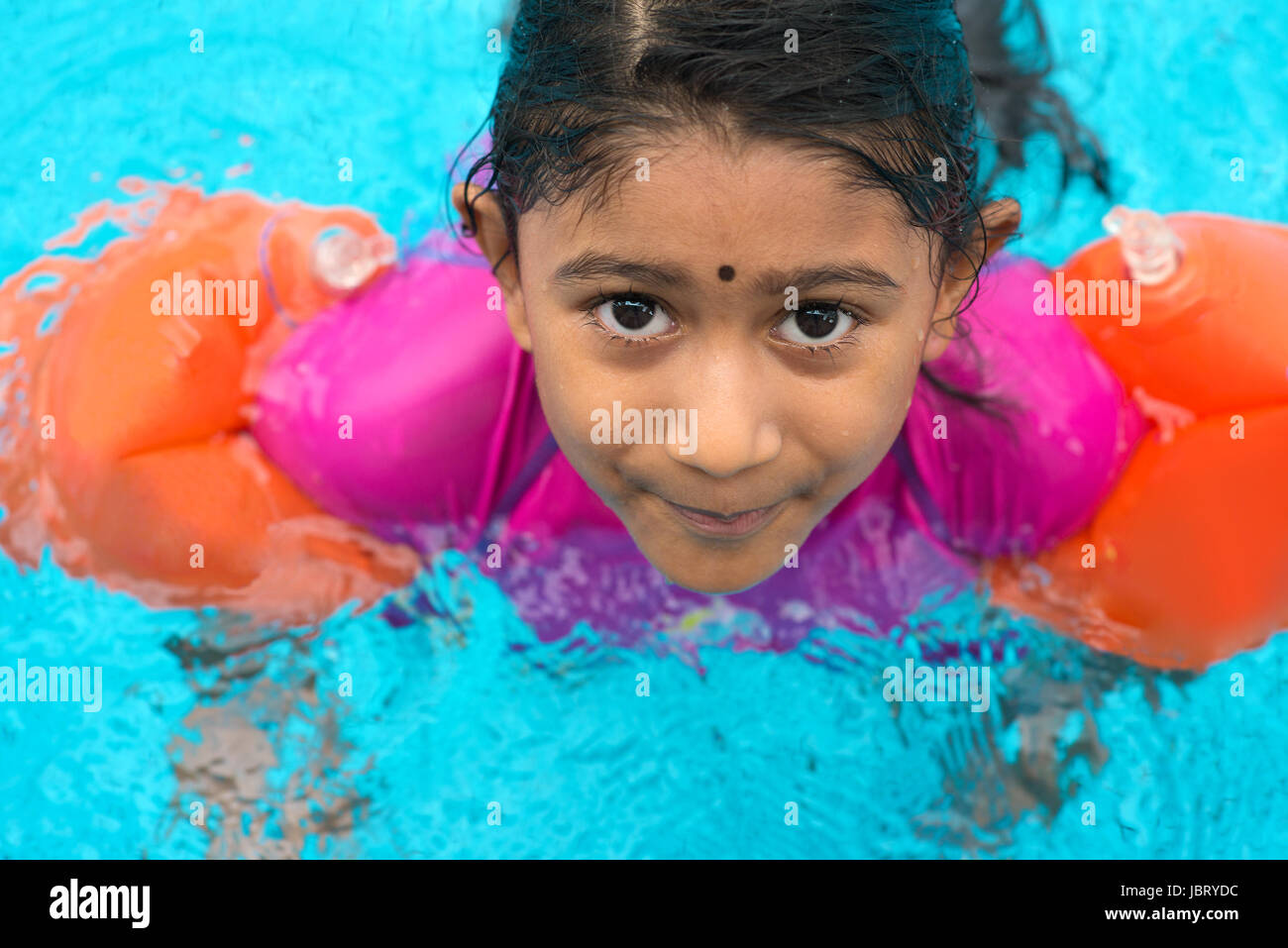Indian child learning swimming in pool. Asian girl in swimmer class ...