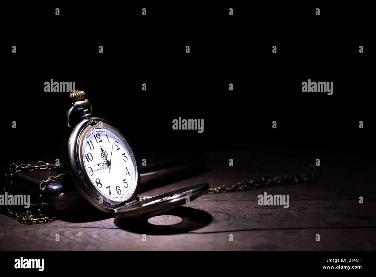 Vintage pocket watch on wooden surface on black background with free ...