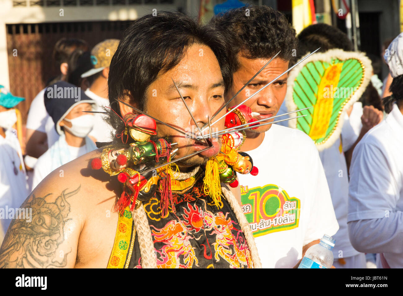 Man with cheeks pierced by multiple skewers in a parade during the Nine ...
