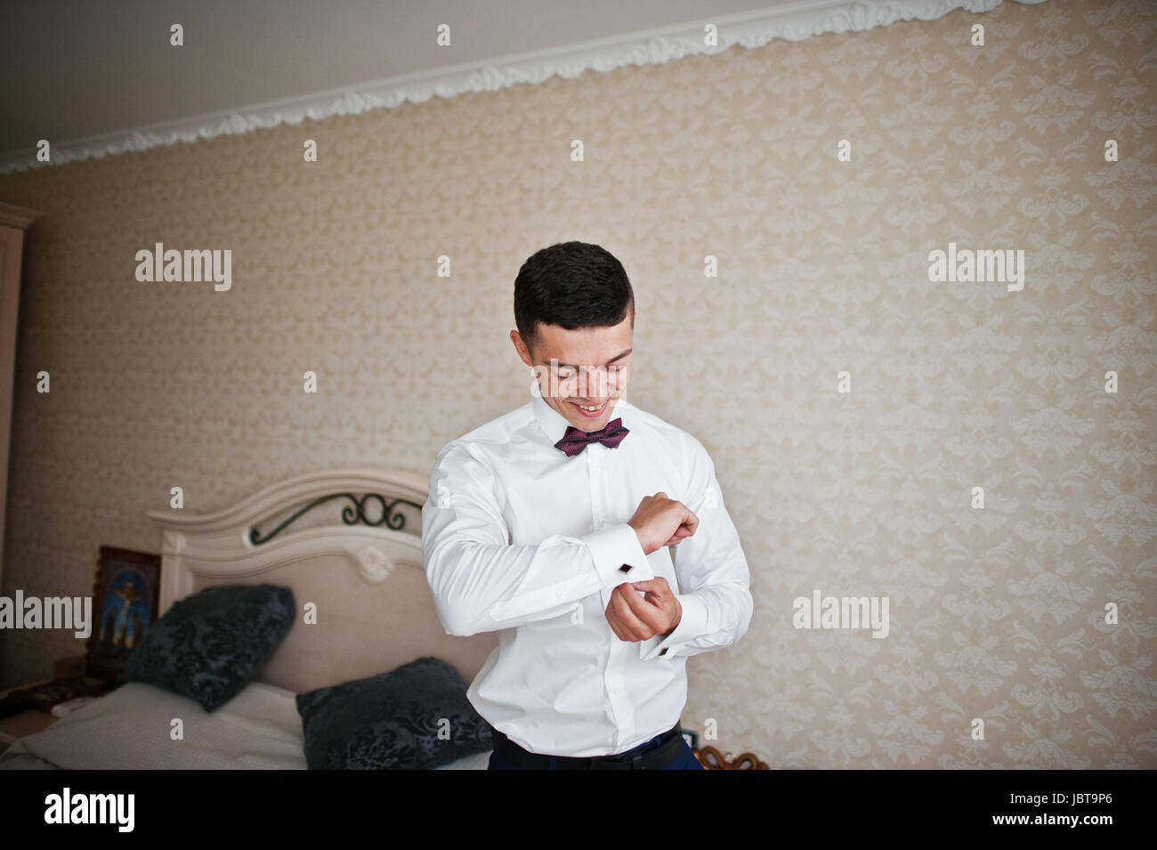 Handsome groom dressing up and getting ready for his wedding in the ...