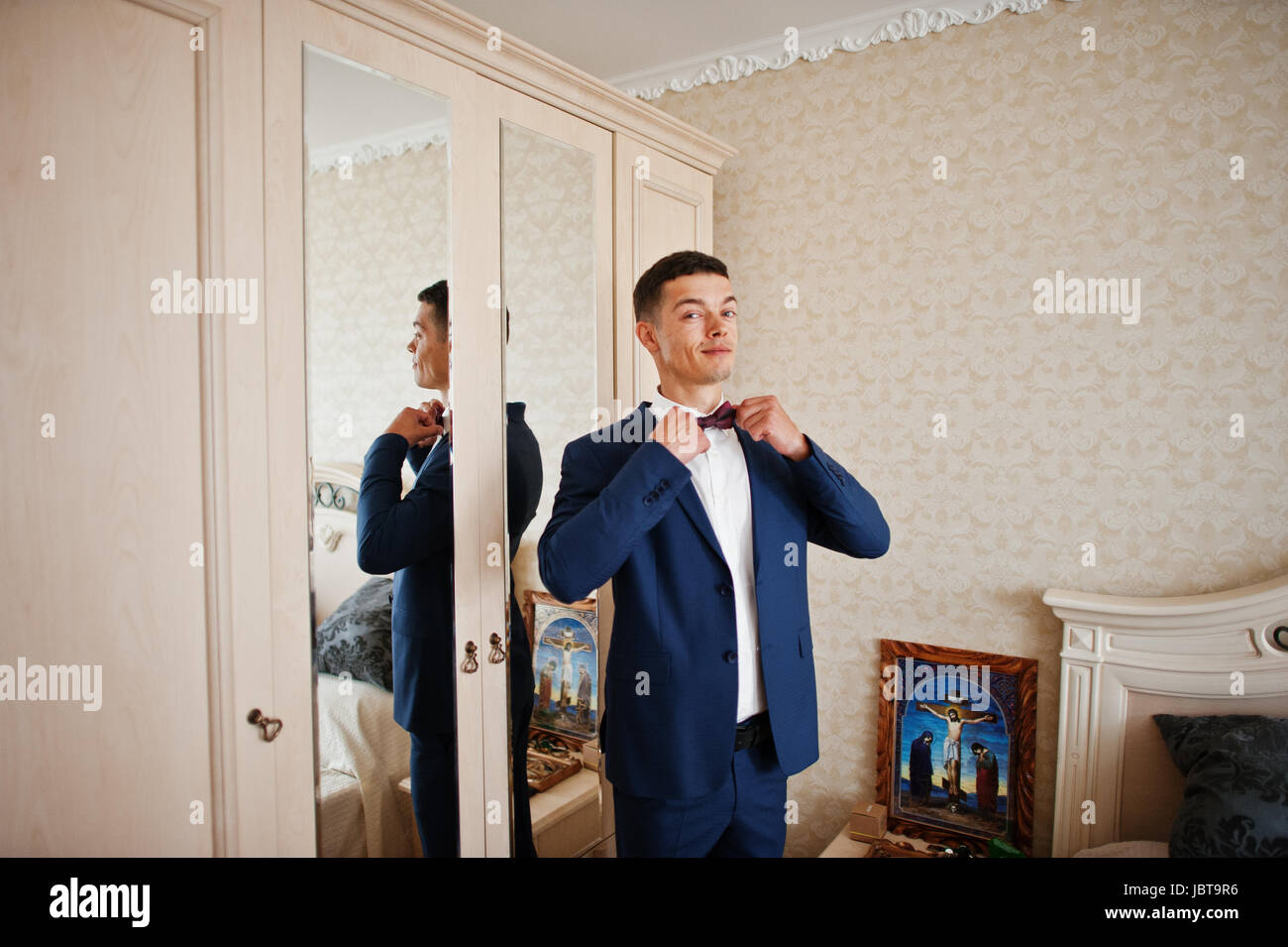Handsome groom dressing up and getting ready for his wedding in the ...