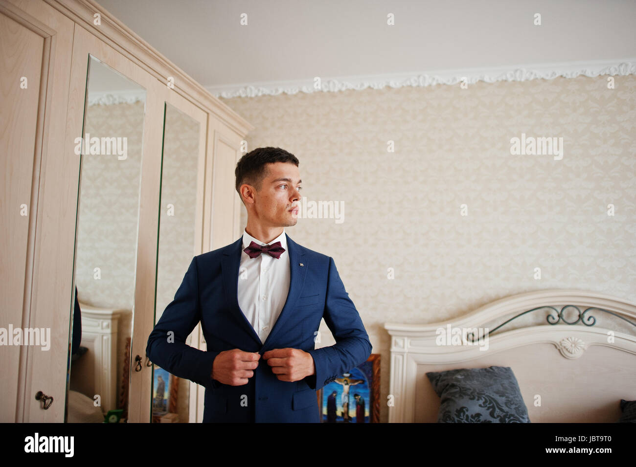 Handsome groom dressing up and getting ready for his wedding in the ...