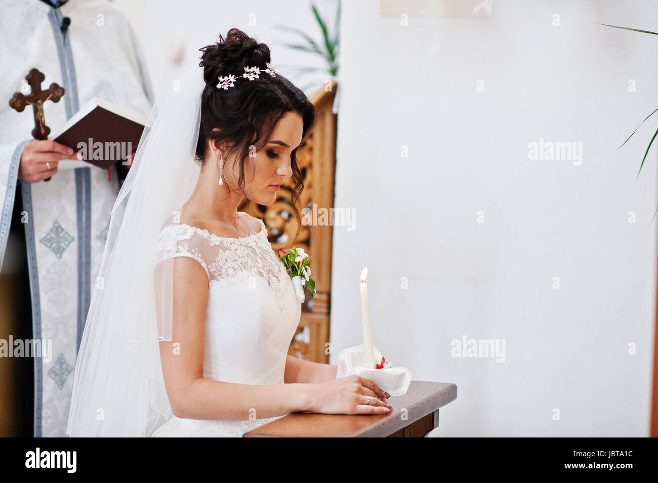 Close up photo of a beautiful bride kneeling in the church during the ...