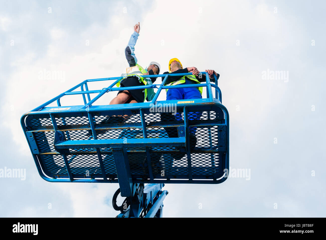 Construction workers on site in hydraulic lifting ramp discussing the ...