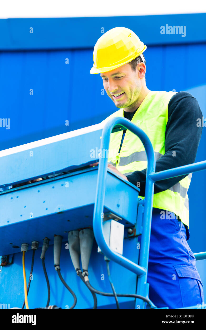 Construction workers or crane driver on site driving hydraulic lifting ...