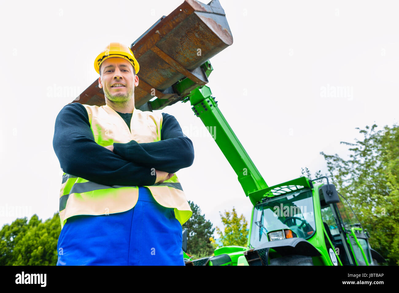Builder or driver standing in front of construction machinery on ...