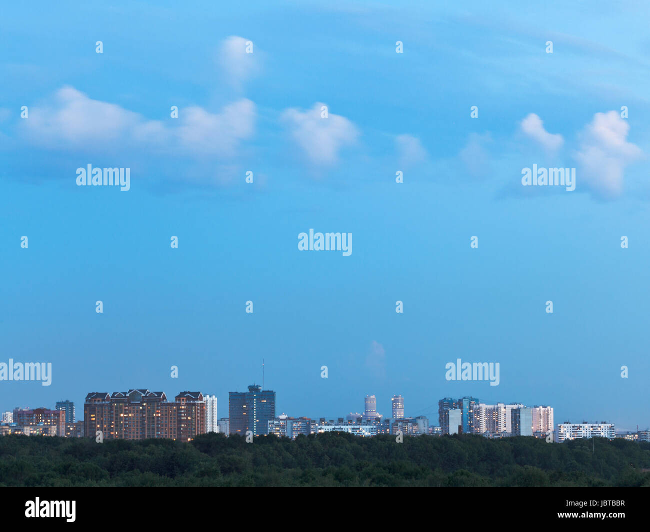 little white clouds in blue dusk sky over city in summer evening Stock ...