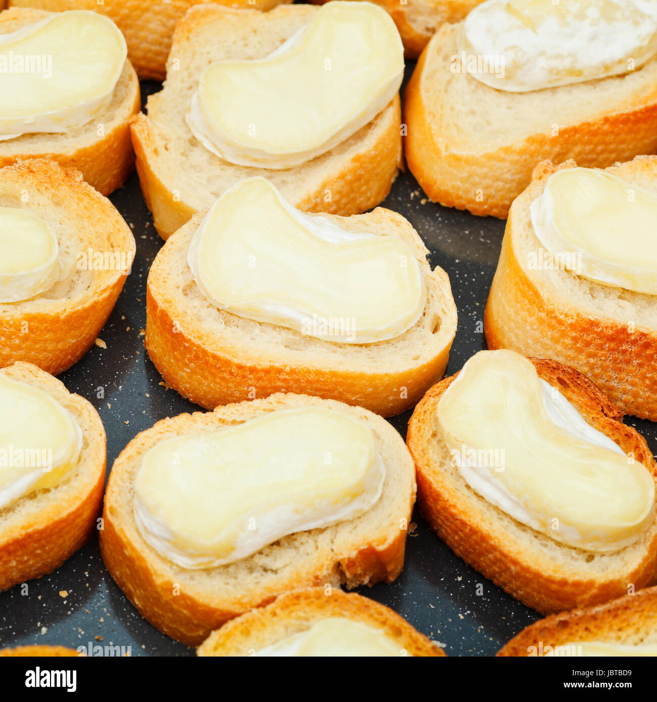 many roasted pieces of bread with melted goat cheese on hot tray Stock ...