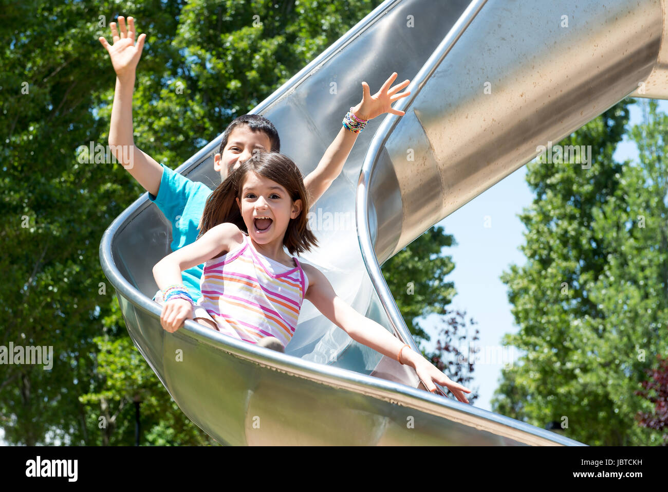 Young kids riding the slider in the park Stock Photo - Alamy