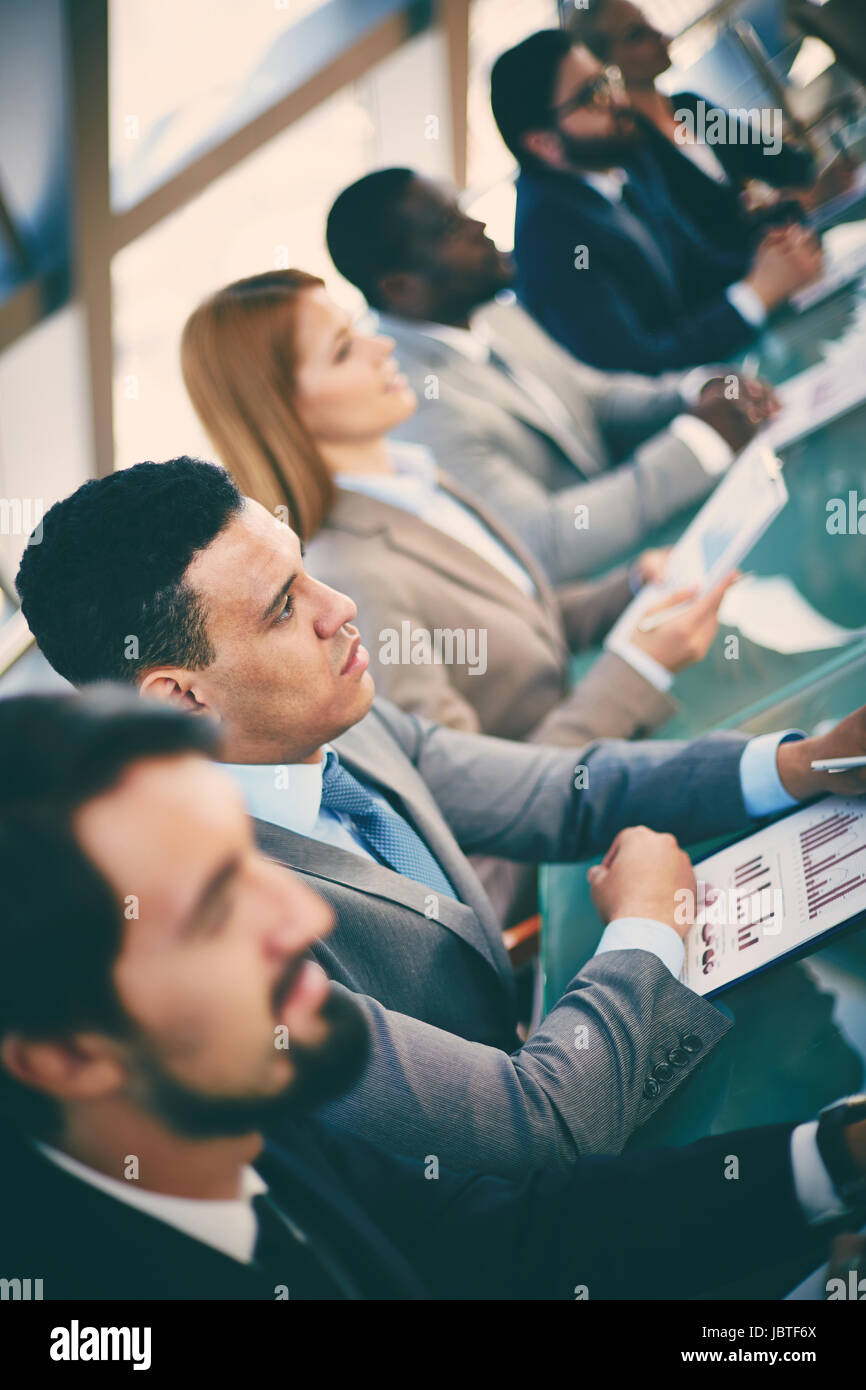 Serious young businessman listening to explanations at seminar on ...