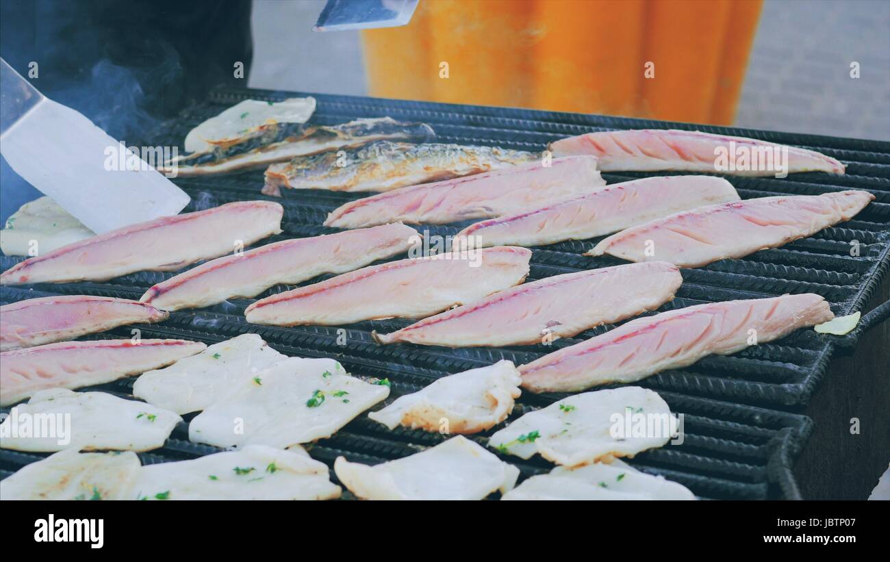 The chef toils over an open grill frying fish, rapans and squid ...
