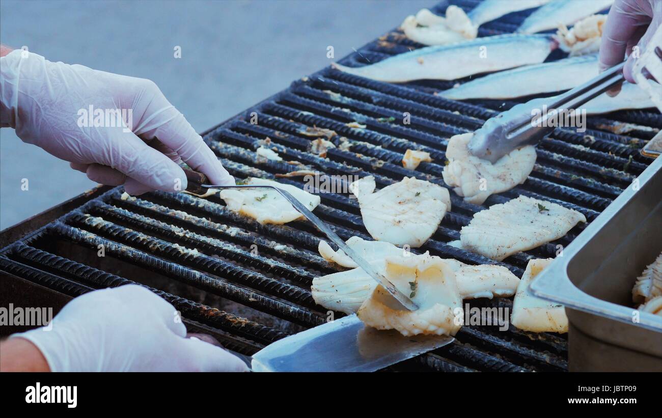 The chef toils over an open grill frying fish, rapans and squid ...