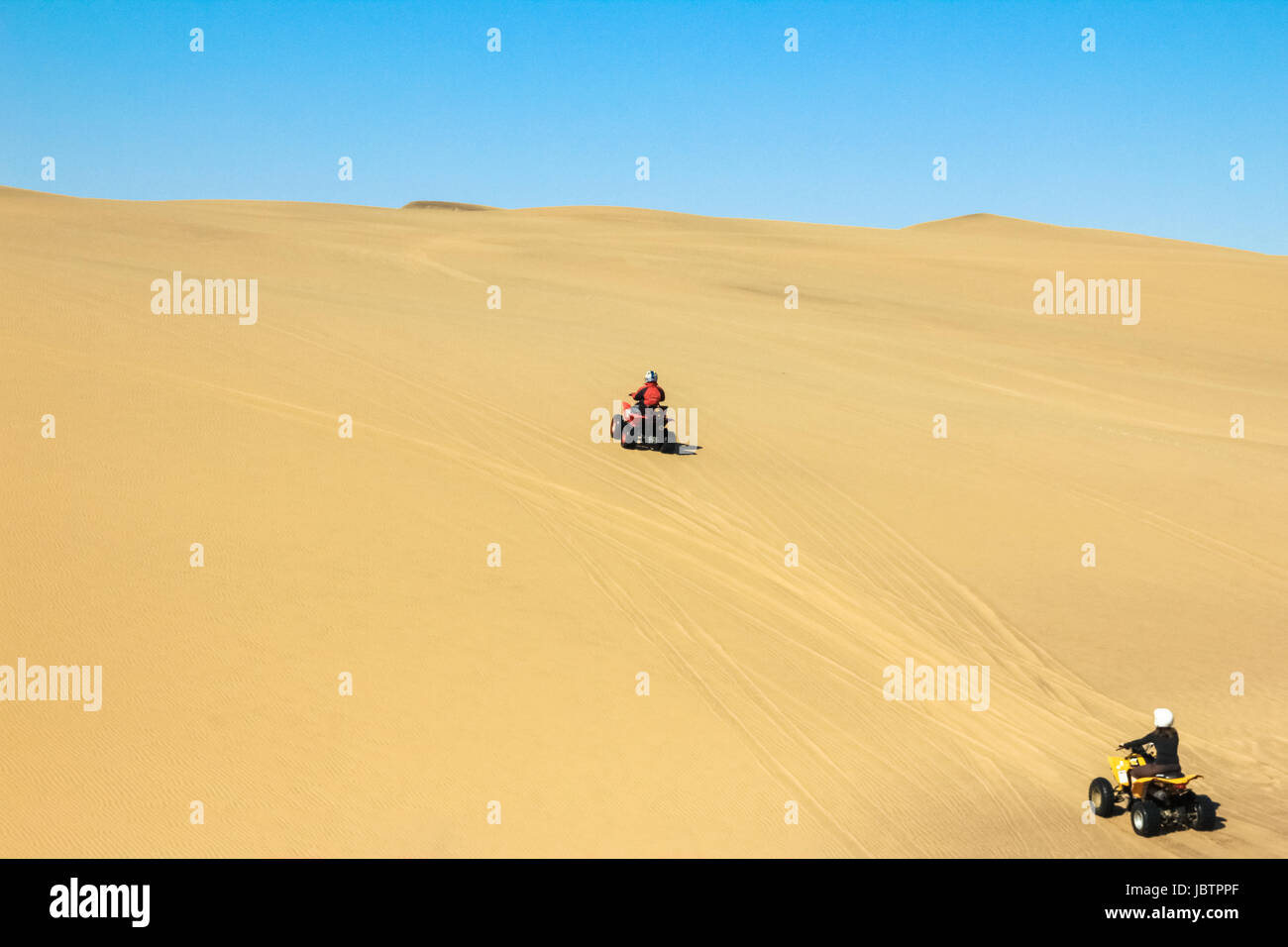 Two happy quad bikers driving in sand dunes. Young active couple in ...