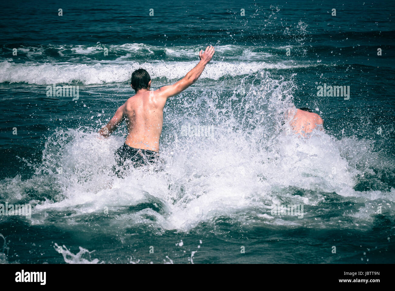 Young people jumping in to sea Stock Photo - Alamy