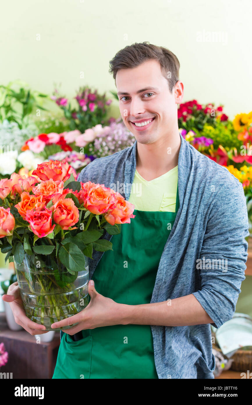 Young handsome florist selling flowers and bouquets in shop Stock Photo ...