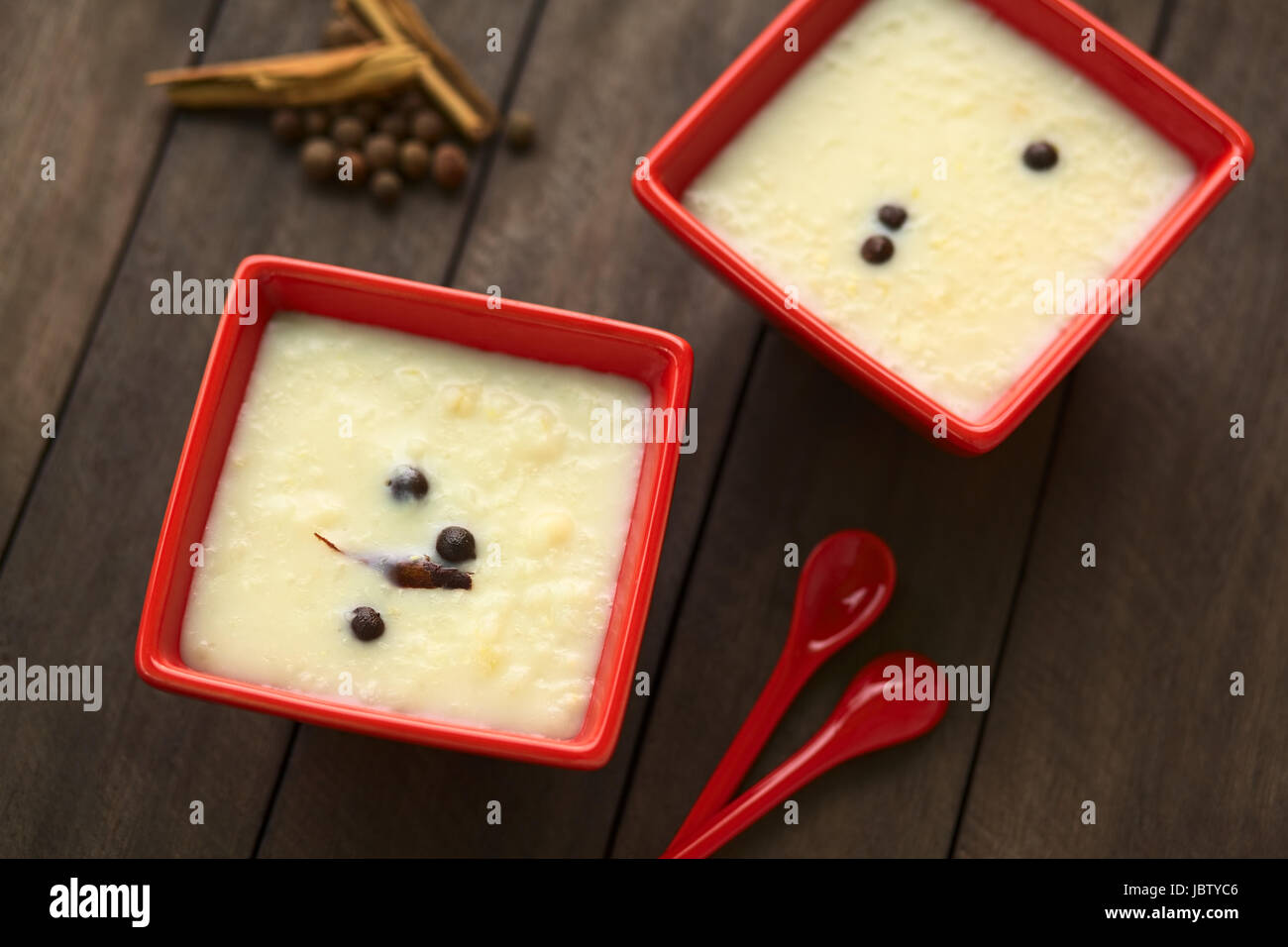 Two red bowls of the Ecuadorian dessert called morocho (coarsely ground ...