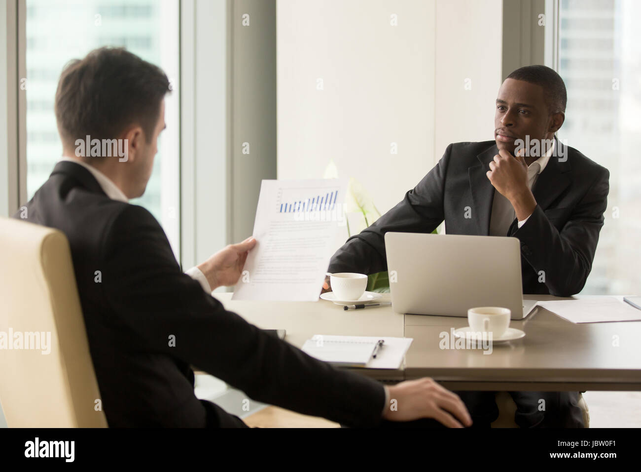 Two multiracial businessmen on corporate meeting in suits discussing ...