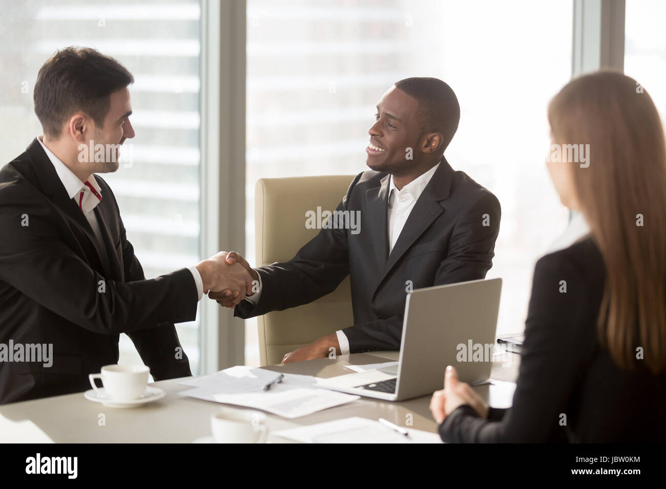 Two cheerful businessmen handshaking at formal meeting, starting ...