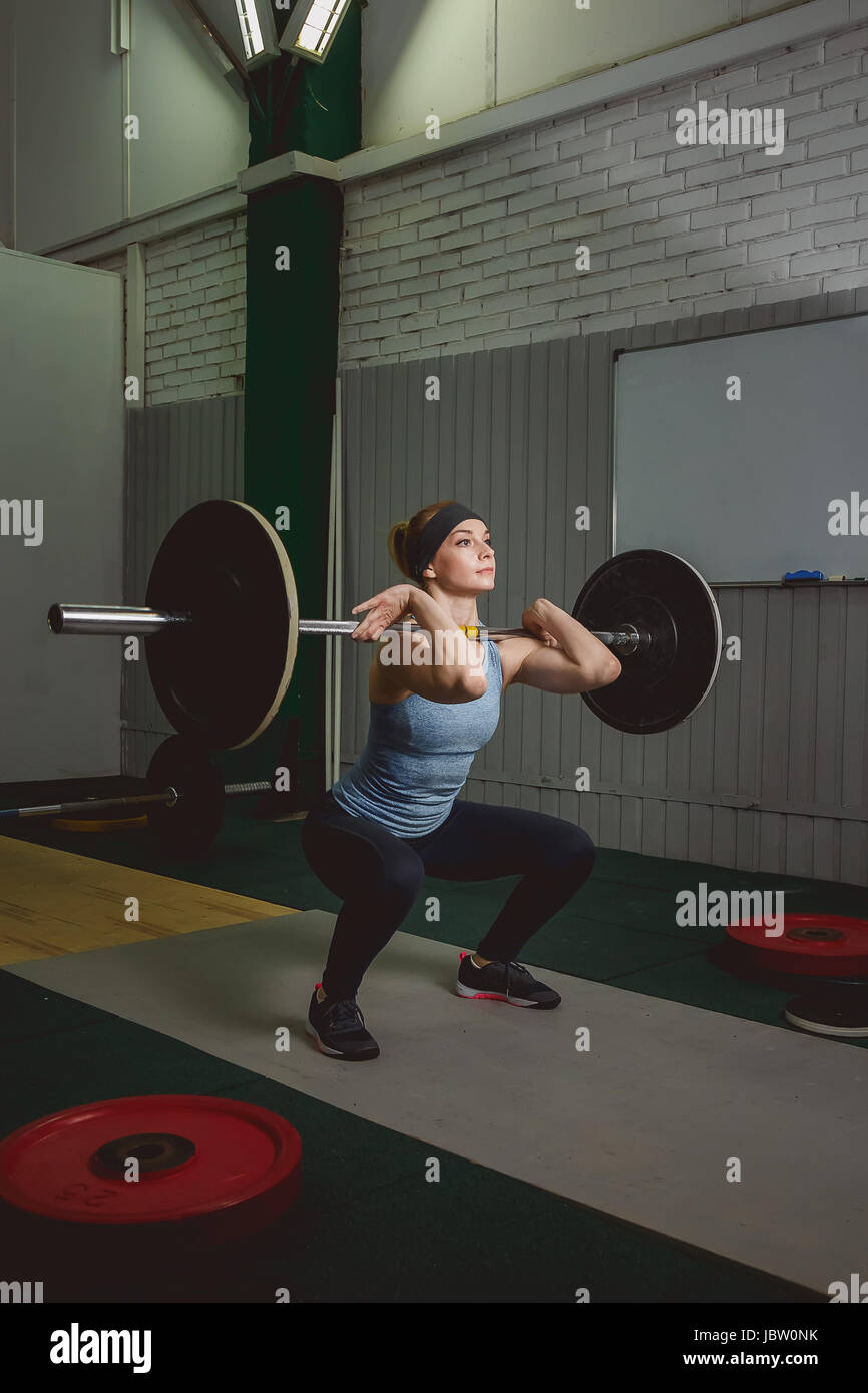 Strong woman lifting barbell as a part of crossfit exercise routine ...