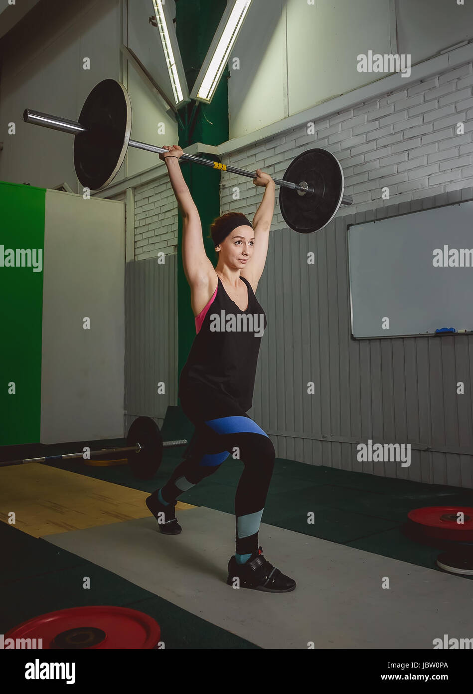 Strong woman lifting barbell as a part of crossfit exercise routine ...