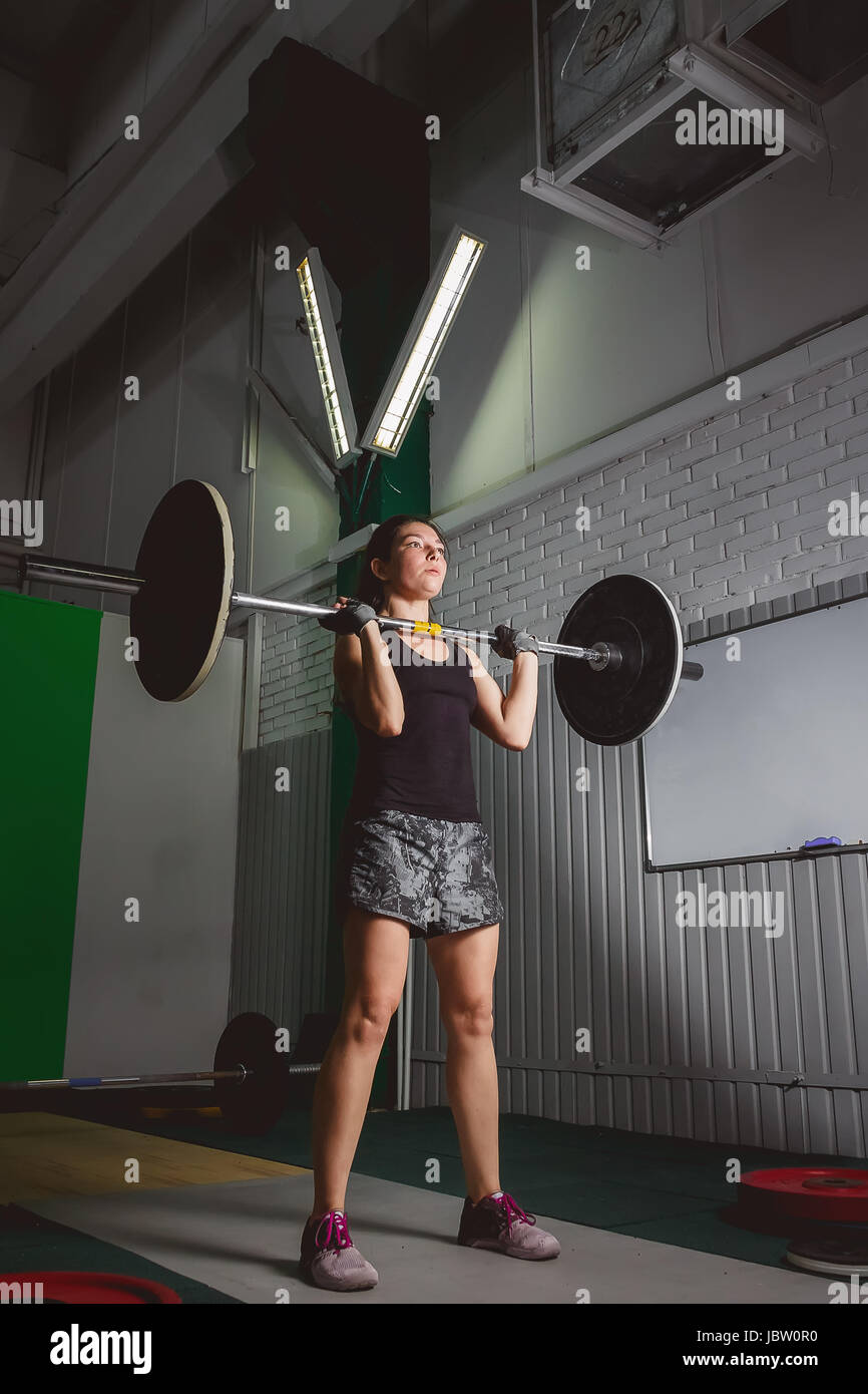 Strong woman lifting barbell as a part of crossfit exercise routine ...