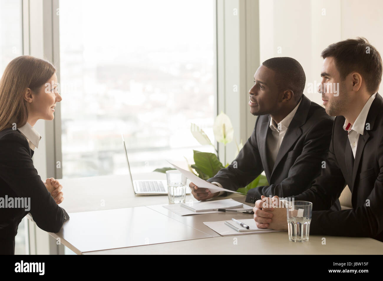 Side view of female applicant introducing herself during job interview ...