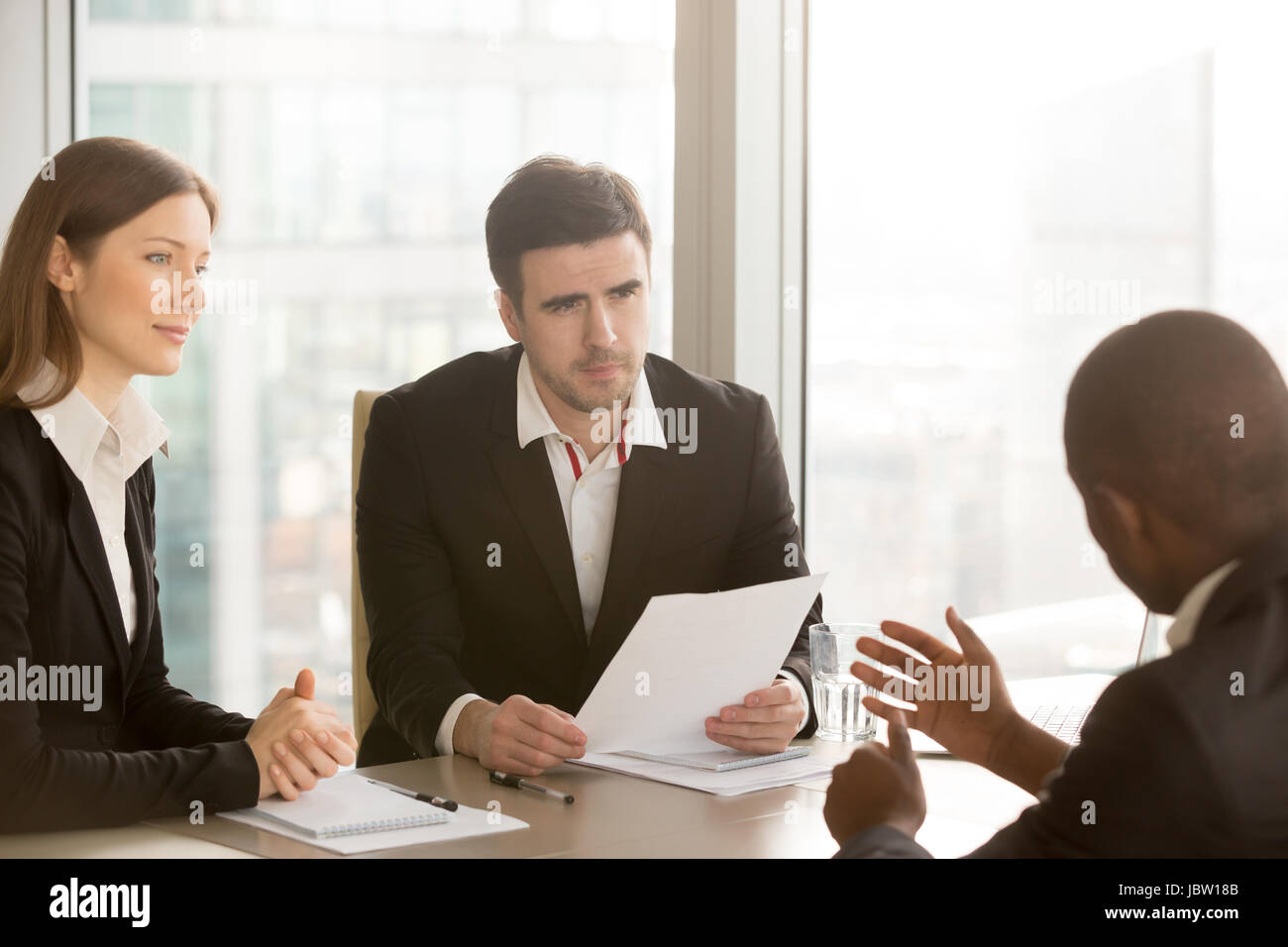 Black businessman trying to convince white doubtful partners to sign ...