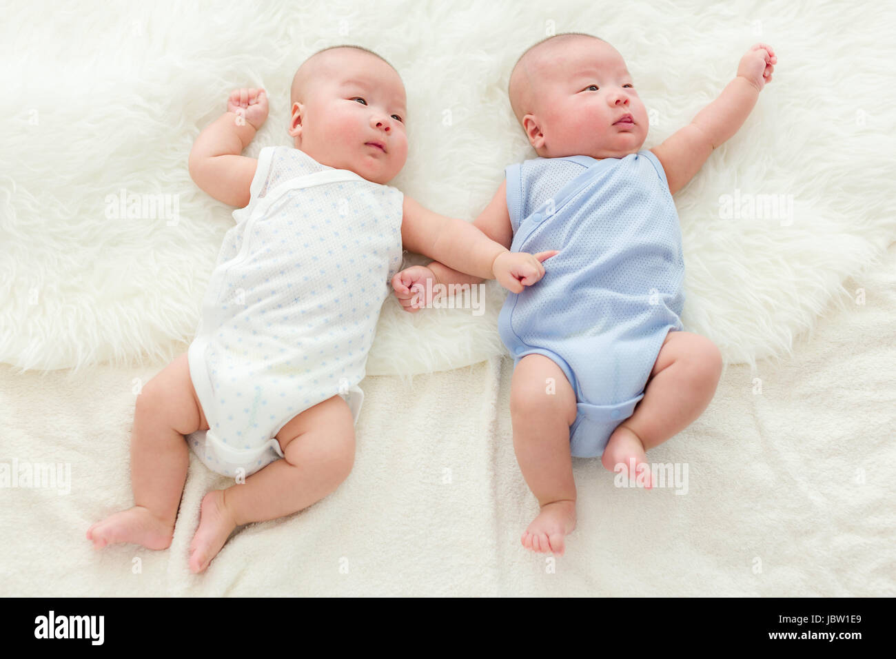 Twin babies laying on bed Stock Photo - Alamy