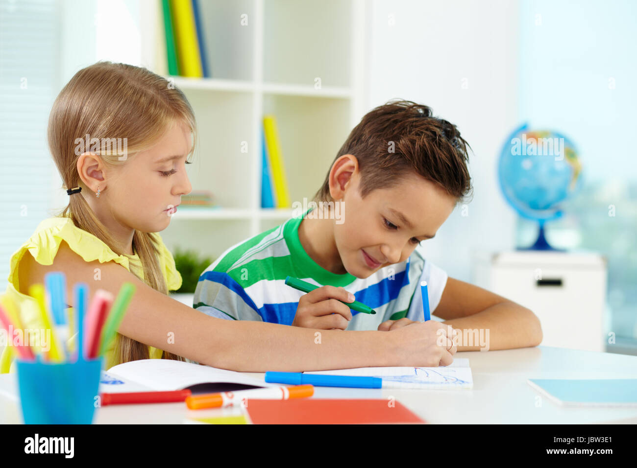 Lovely girl and her classmate drawing together at lesson Stock Photo ...