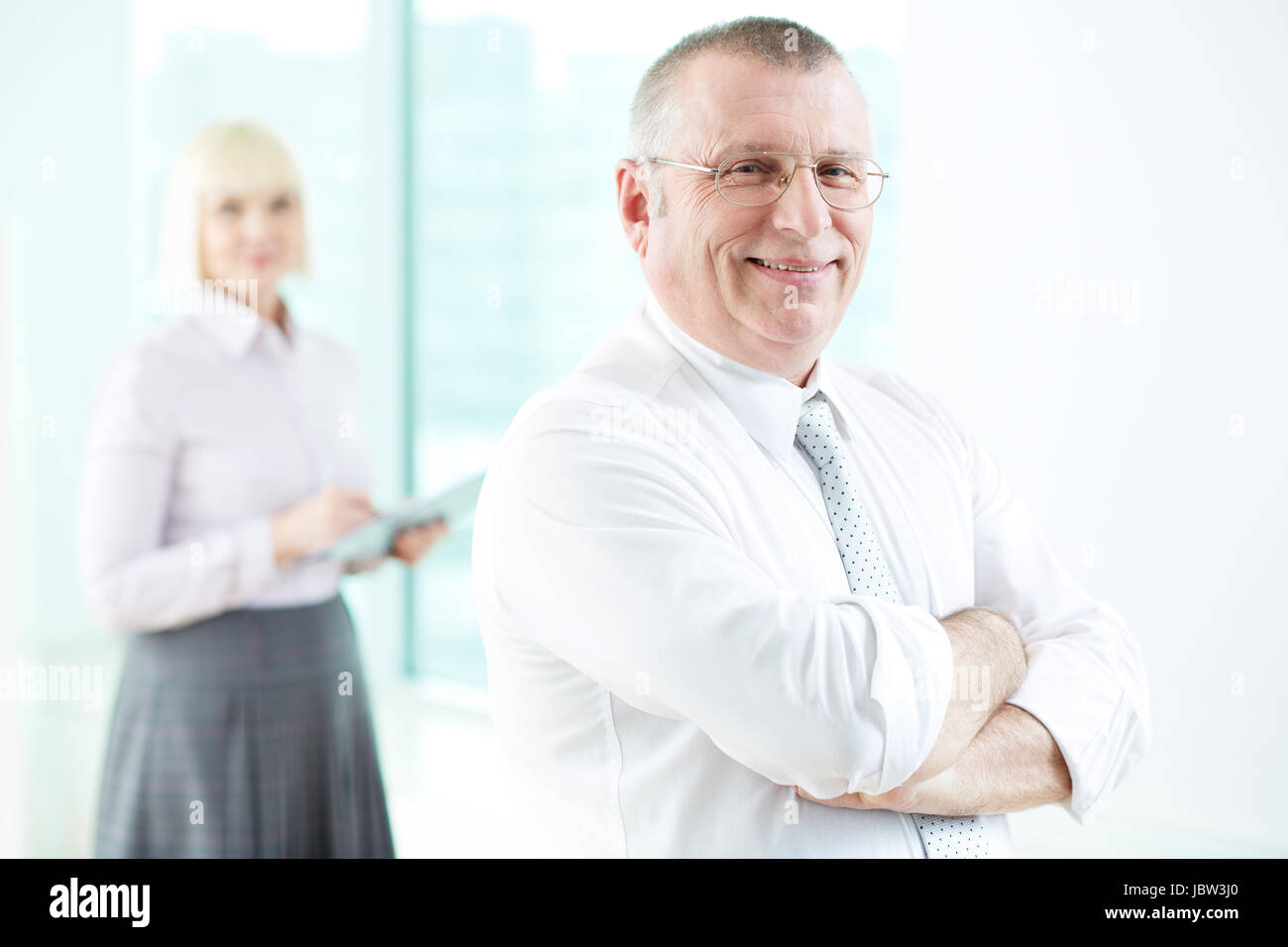 Portrait of smiling boss looking at camera with female standing on ...