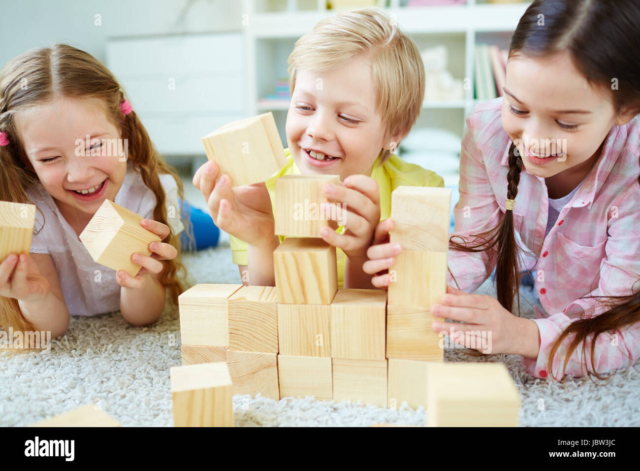 Three little friends playing with wooden bricks Stock Photo - Alamy