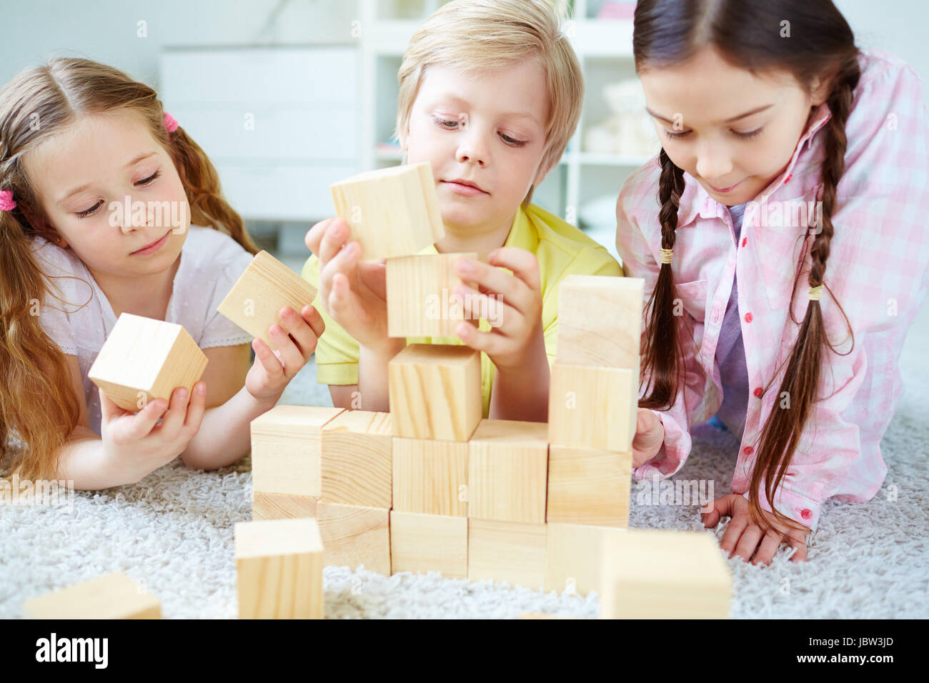 Three little friends playing with wooden bricks Stock Photo - Alamy