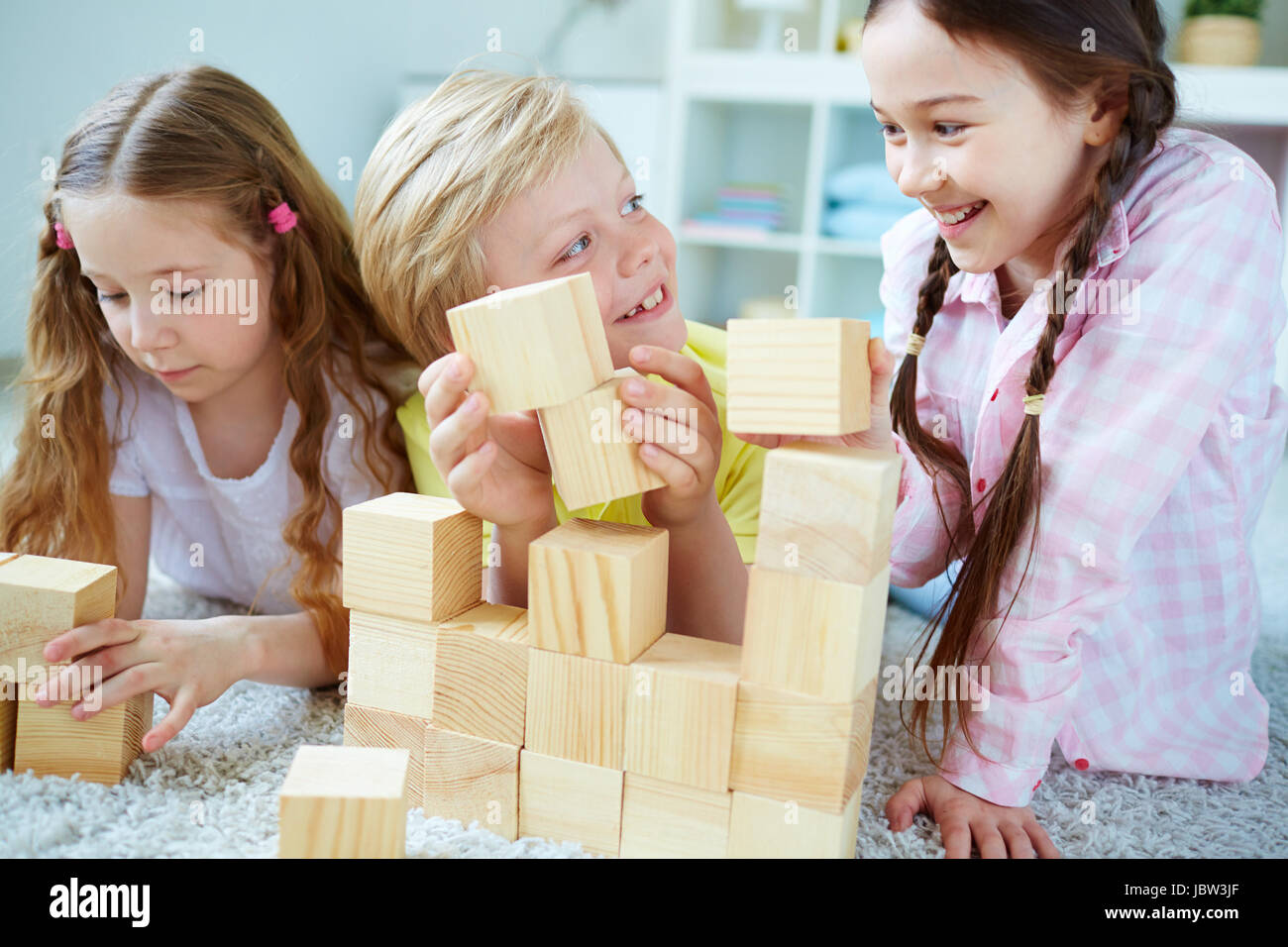 Three little friends playing with wooden bricks at leisure Stock Photo ...