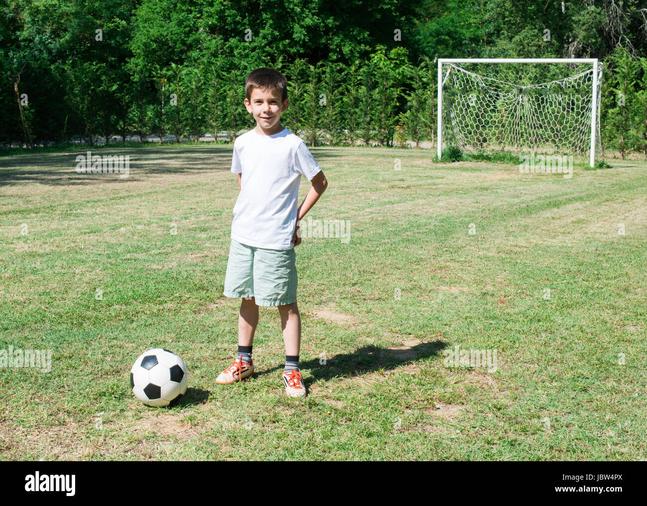 Child playing football in a stadium. Trees on the background Stock ...