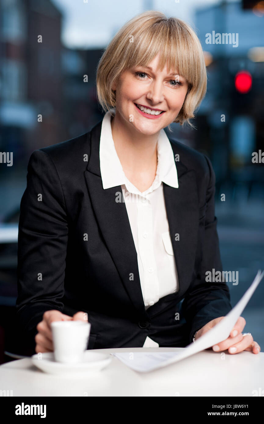 Smiling woman checking business reports carefully in a cafe Stock Photo ...