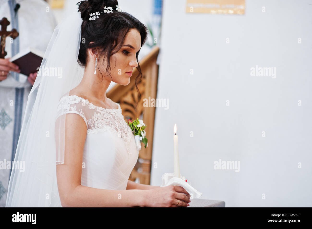 Close up photo of a beautiful bride kneeling in the church during the ...