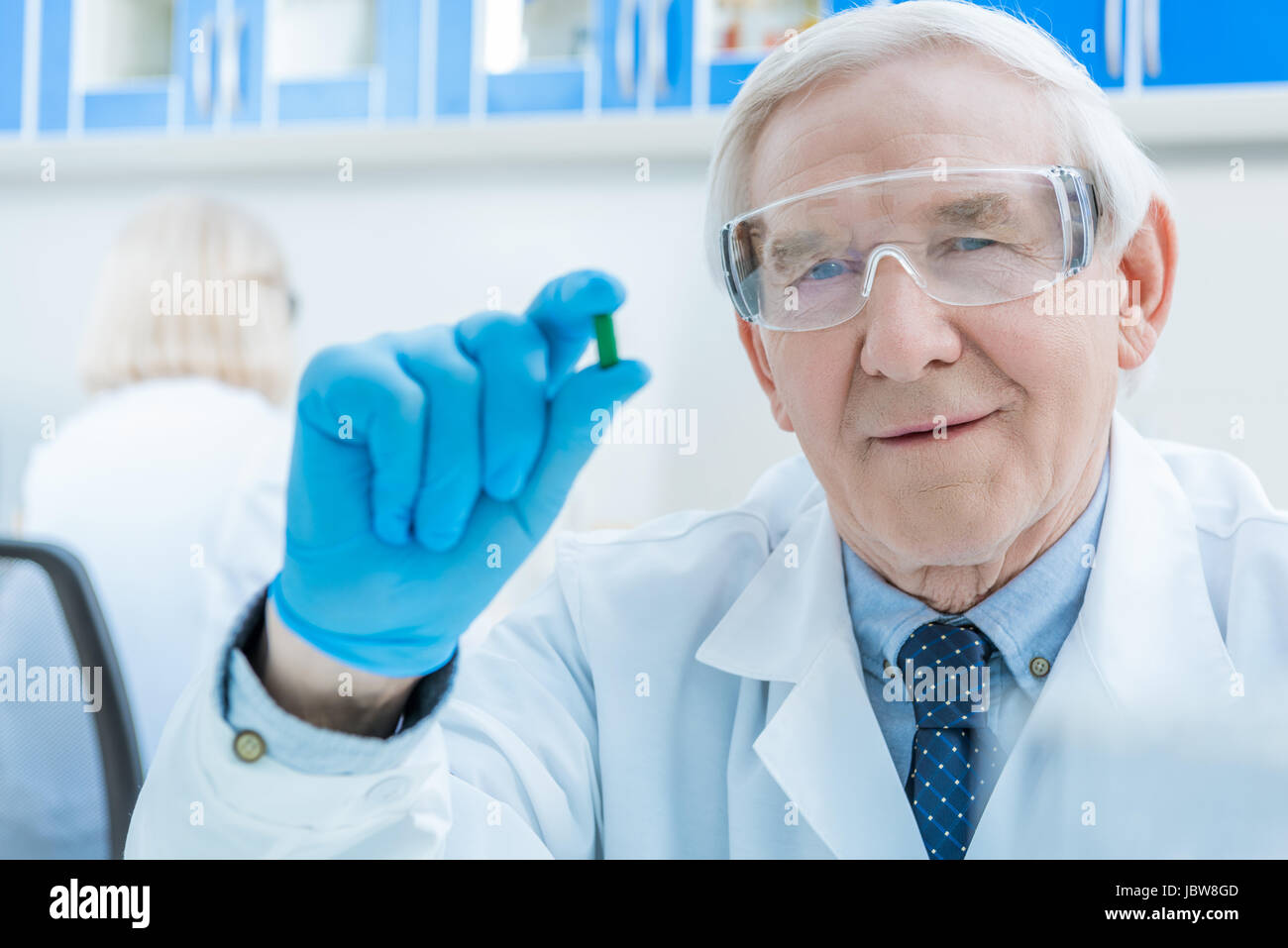 portrait of senior man scientist showing pill in hand in lab Stock ...